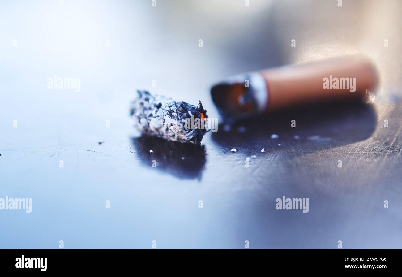Smoke, ash and burning cigarette butt on table, tobacco addiction ...