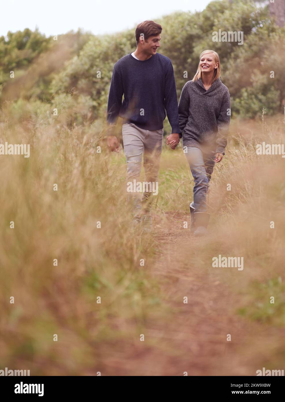 Hand-in-hand in nature. A young couple strolling hand in hand through a ...