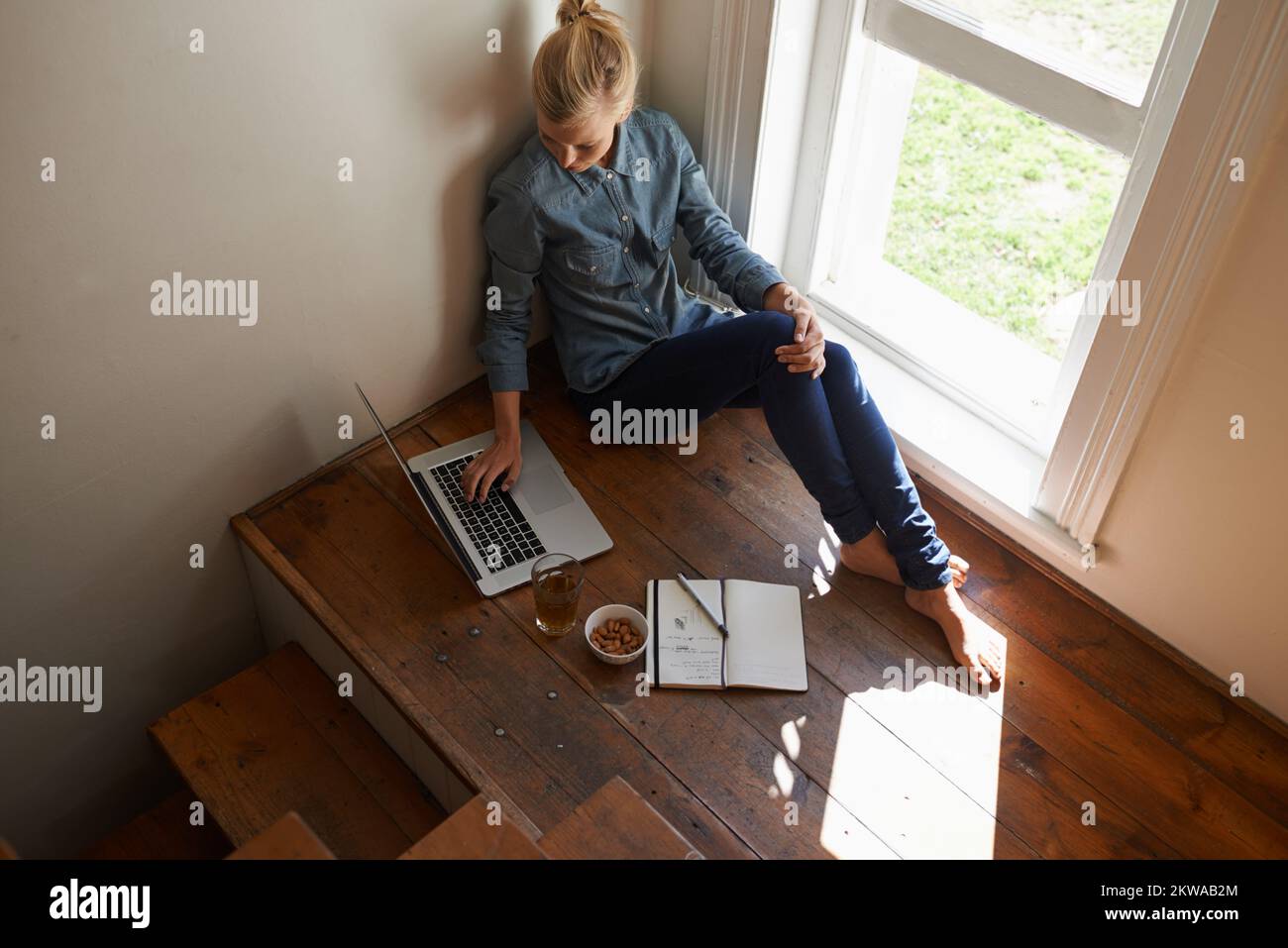 Finding a quiet place at home. A young woman sitting on the floor by a ...