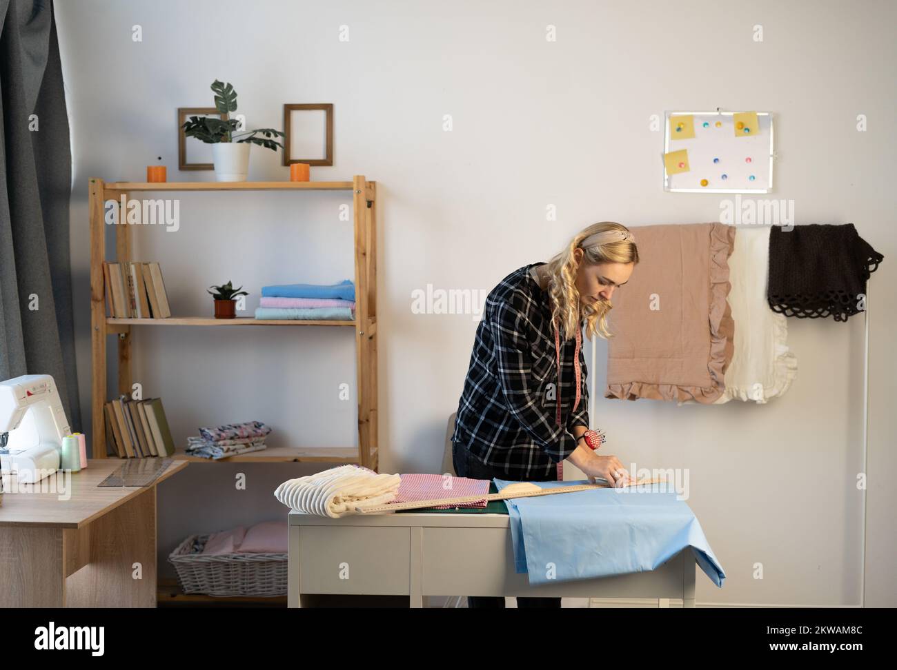 Female tailor measuring of fabric for pattern cutting in workshop ...