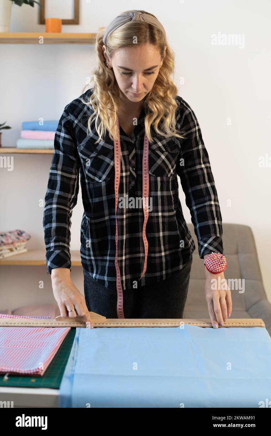 Portrait of designer at work with fabric. Tailor measuring necessary ...