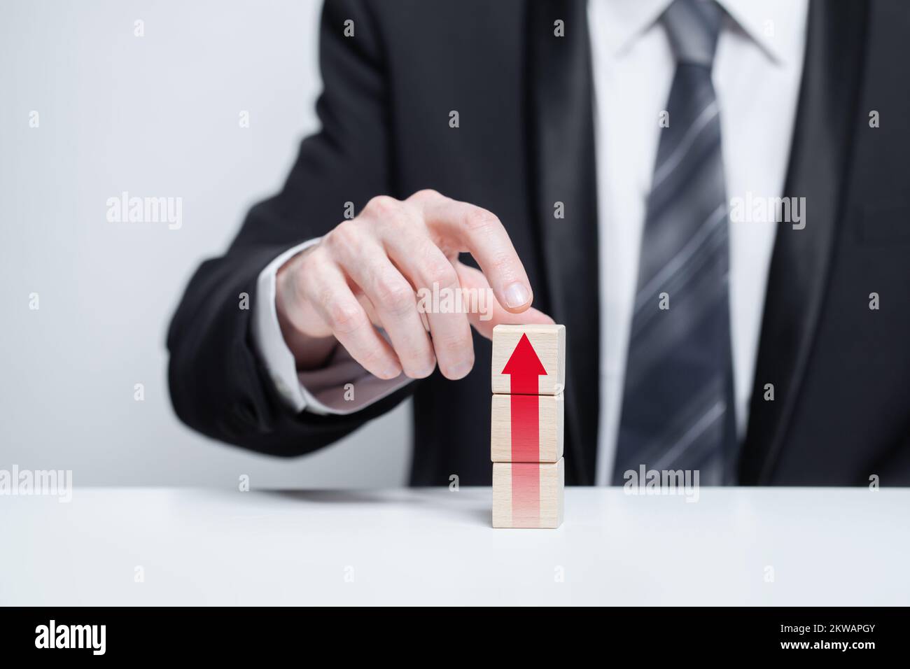 Wooden blocks with red arrow icon, businessman in suit holding cube on ...
