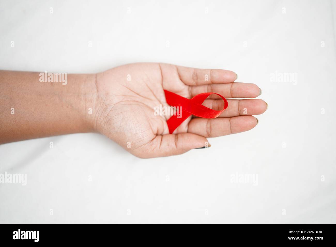 A women holding red ribbon in one hand representing Worlds HIV Aids Day ...