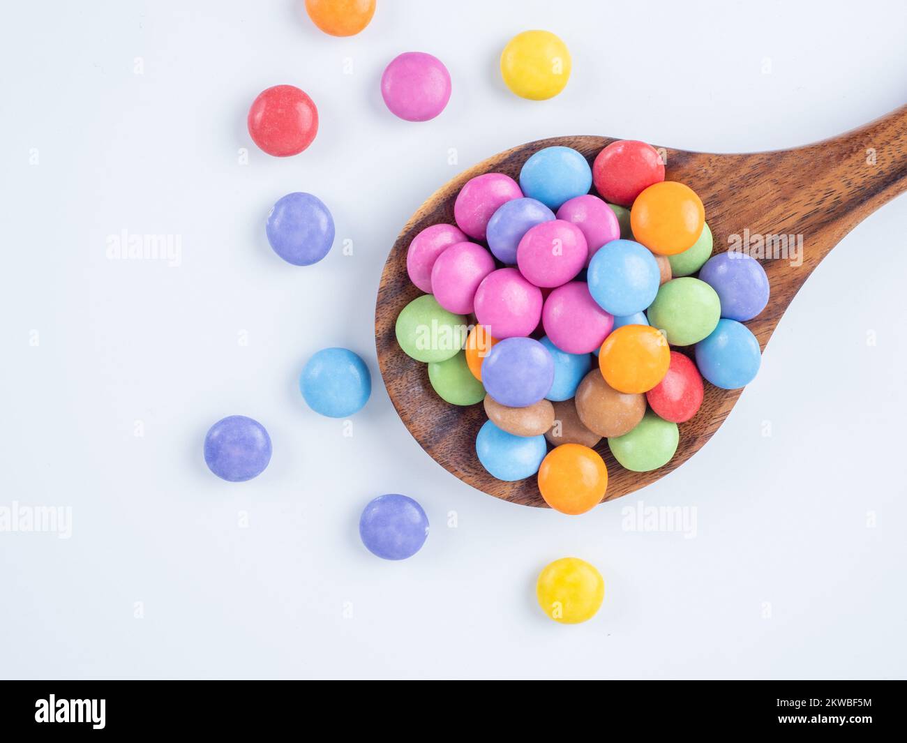 Bright multi coloured sugar coated chocolate candy presented on a teak ...