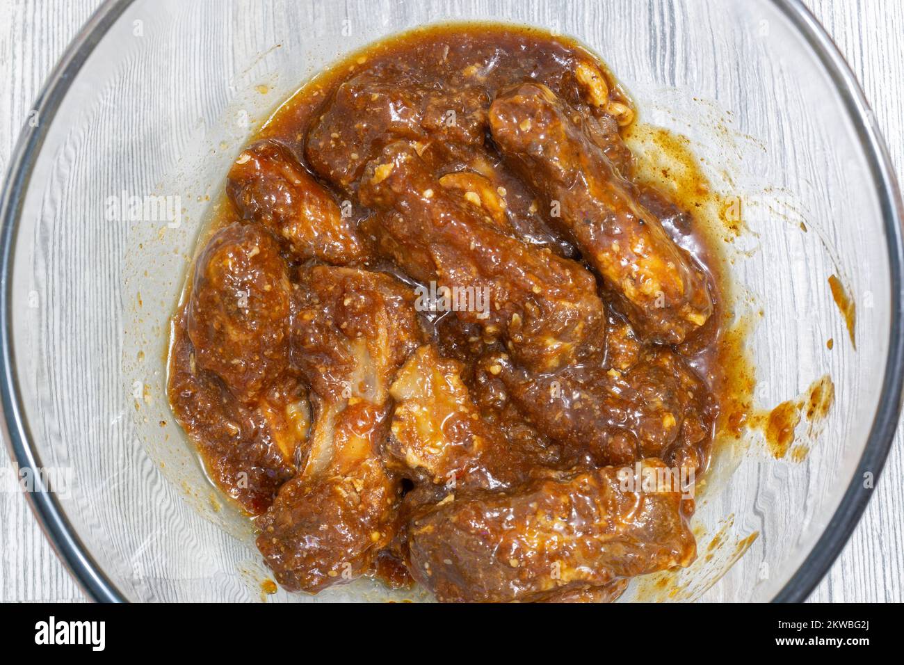 Pork mini ribs with a spicy barbecue sauce marinade, in a glass bowl ...