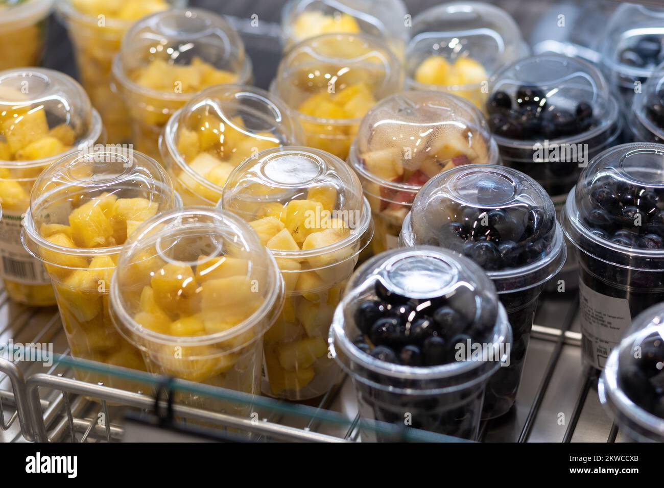 Close up of plastic cups filled with chopped fruits and berries. Eco ...