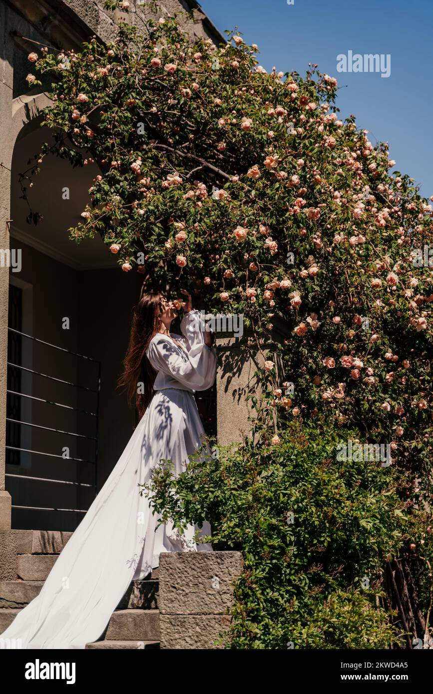a beautiful woman in a white flowing long dress stay near a beautiful ...