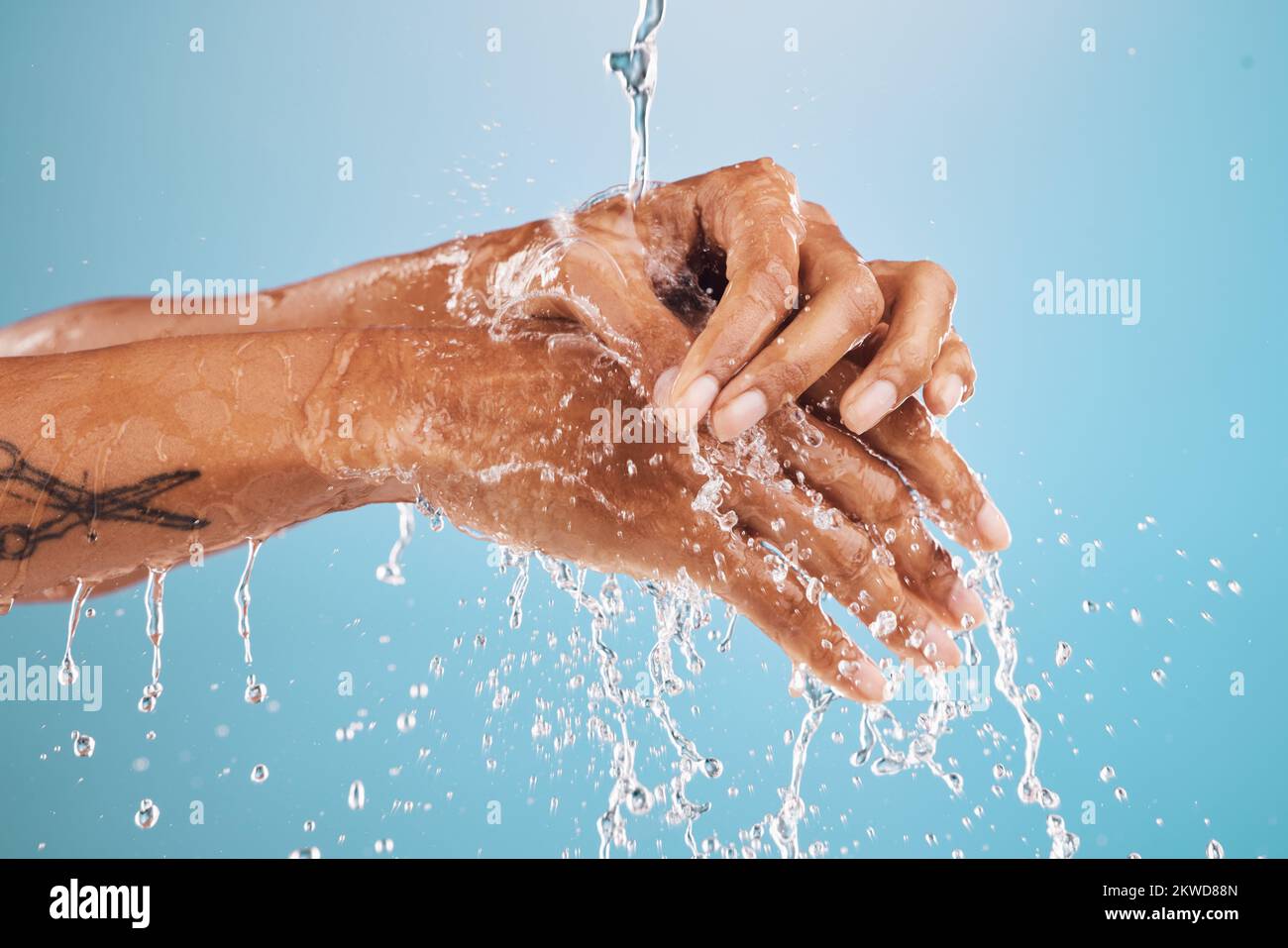 Black woman, water splash or washing hands on blue background in studio ...