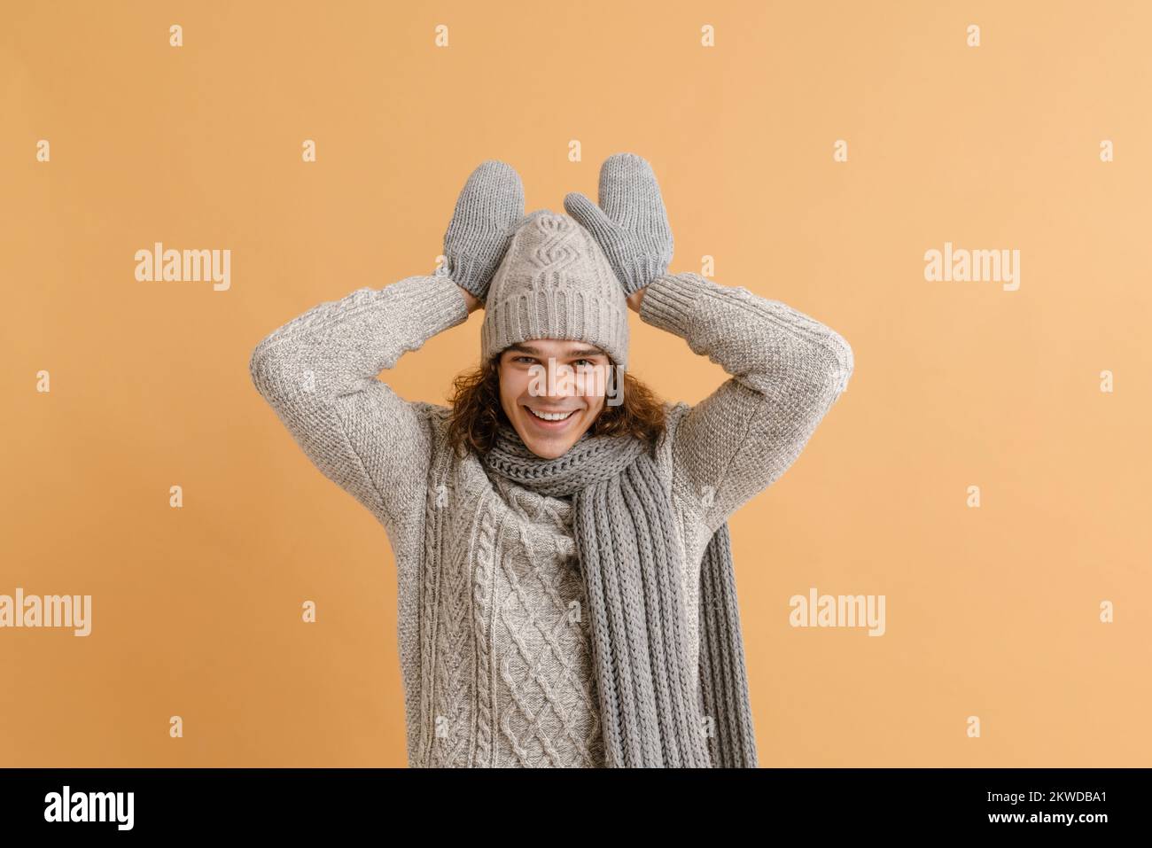 Young handsome man with long hair in sweater and winter hat, scarf and ...