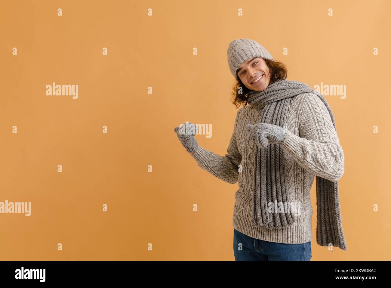 Young handsome man with long hair in sweater and winter hat, scarf and ...