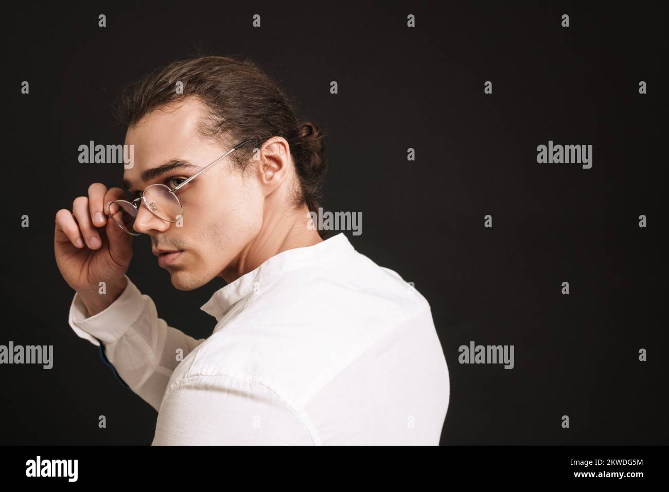 Young handsome man in white shirt adjusting glasses and looking ...