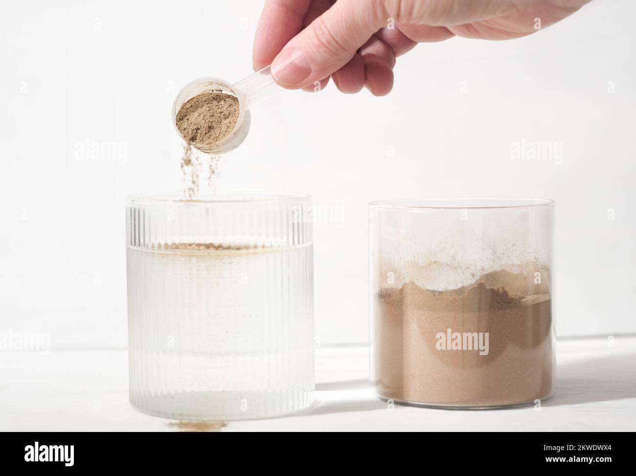 woman pouring plant based protein powder into a glass of water. plant ...