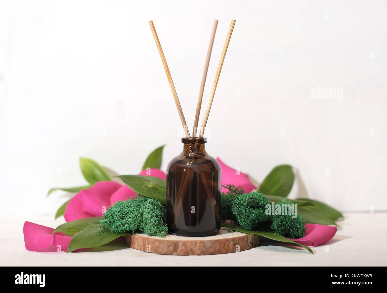 home scent, reed diffuser on wooden podium with green leaves and petals ...