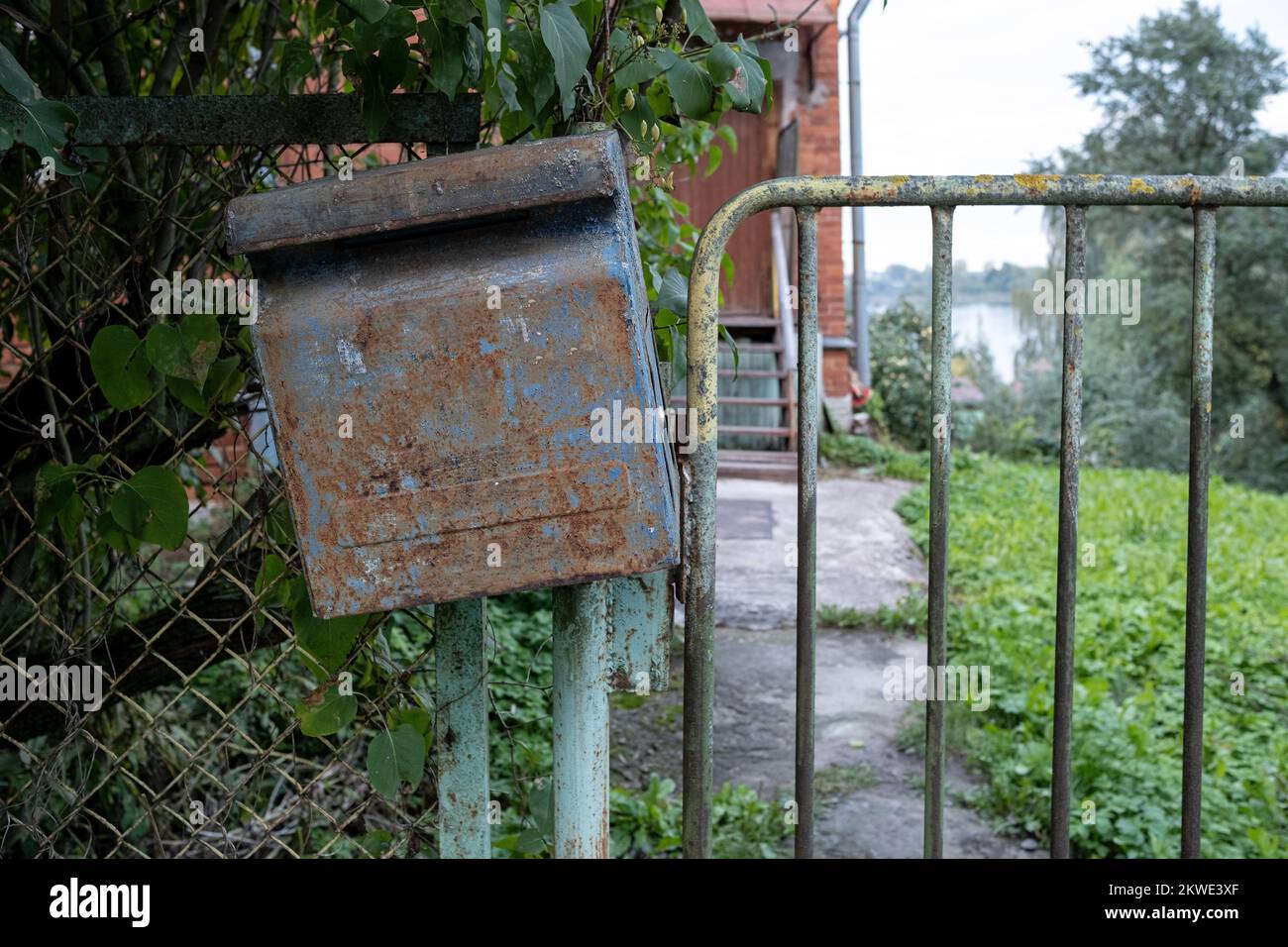 Mailbox is hanging on the fence. Old, rusty mailbox with peeling paint ...