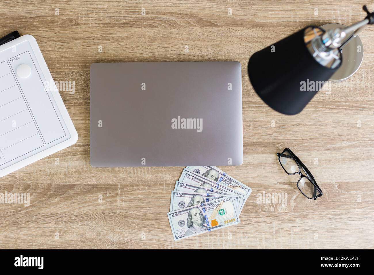 Top view of desktop with weekly planner, laptop, glasses, lamp and cash ...