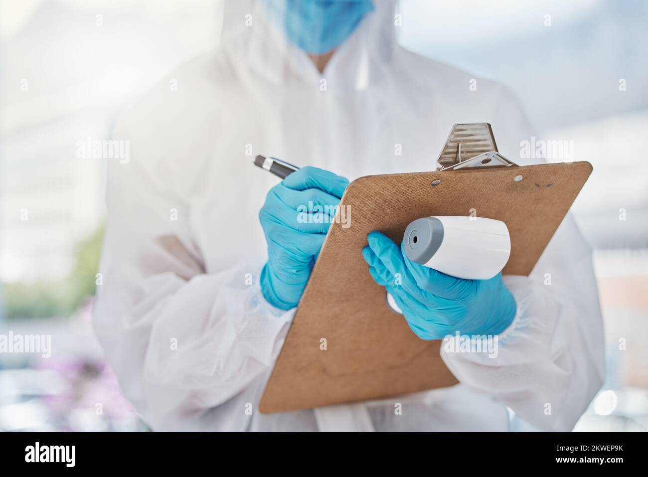 Doctor writing covid safety report with laser thermometer for fever ...