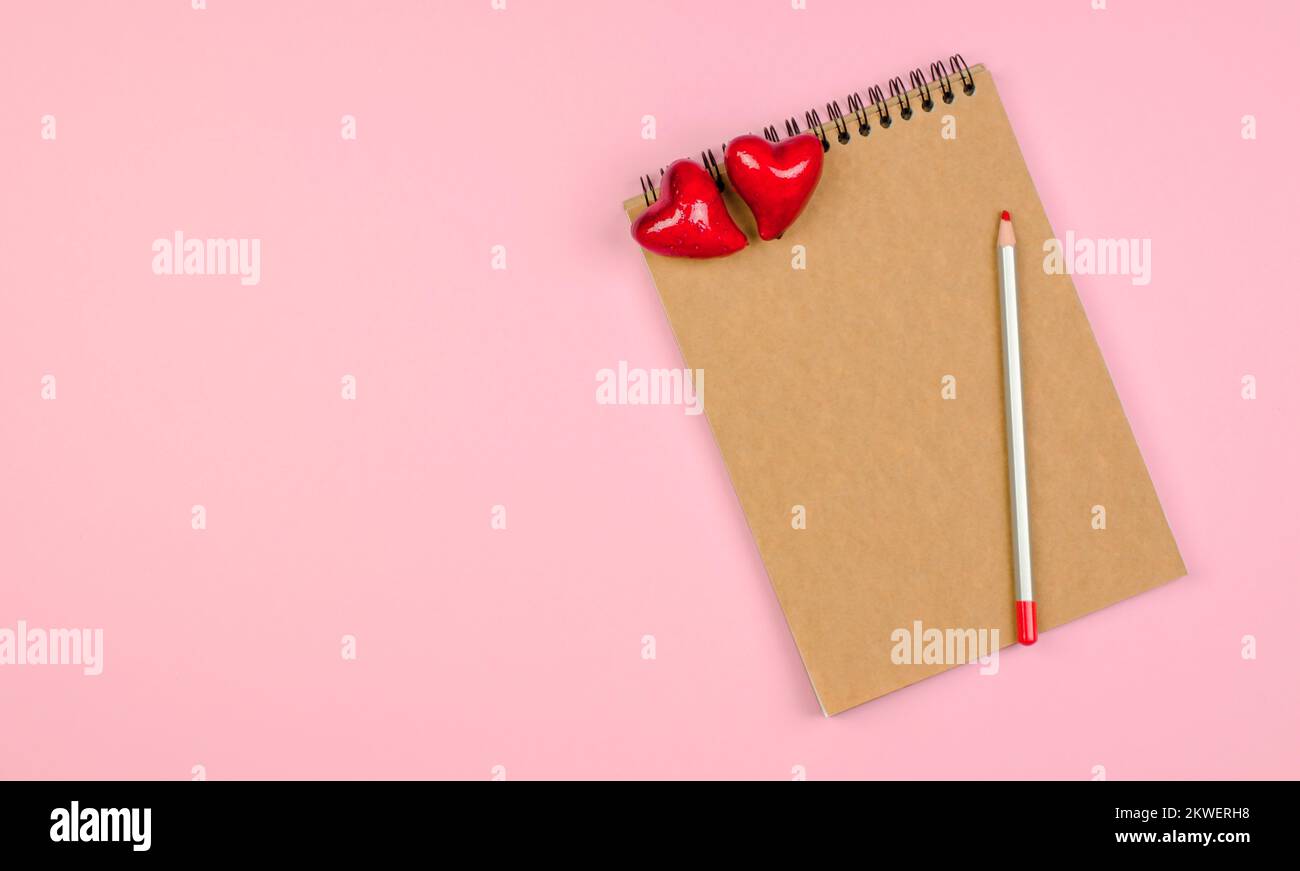 Blank notepad with craft paper and a pencil on a pink background with ...