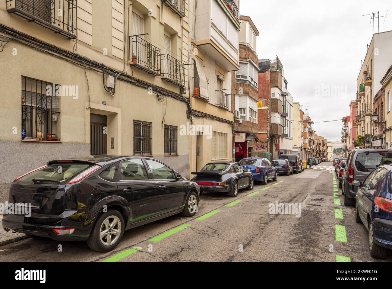 A street in a modest neighborhood of Madrid with cars parked in the ...