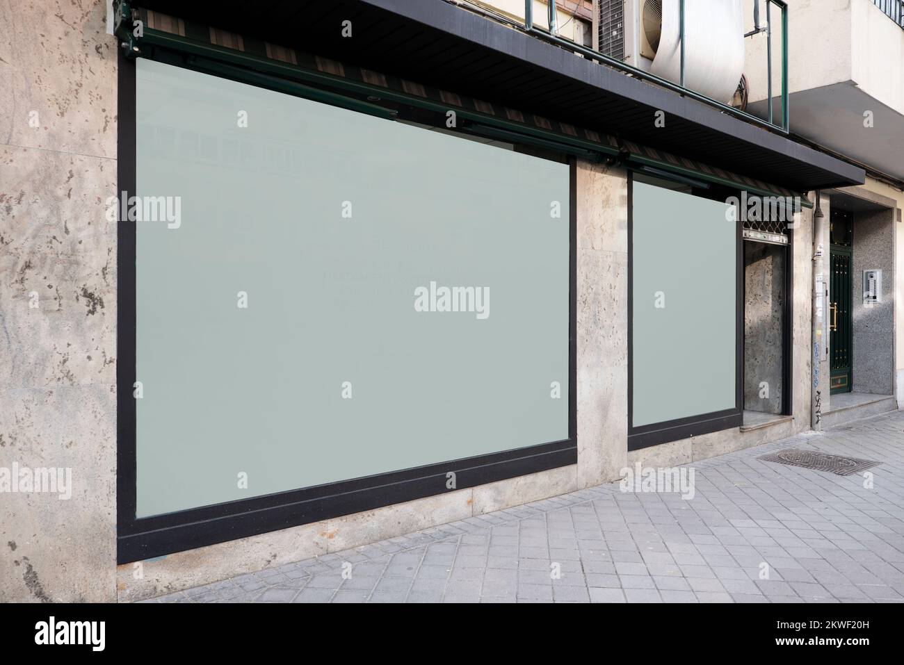 Front of a commercial premises with two white glass windows and faded ...