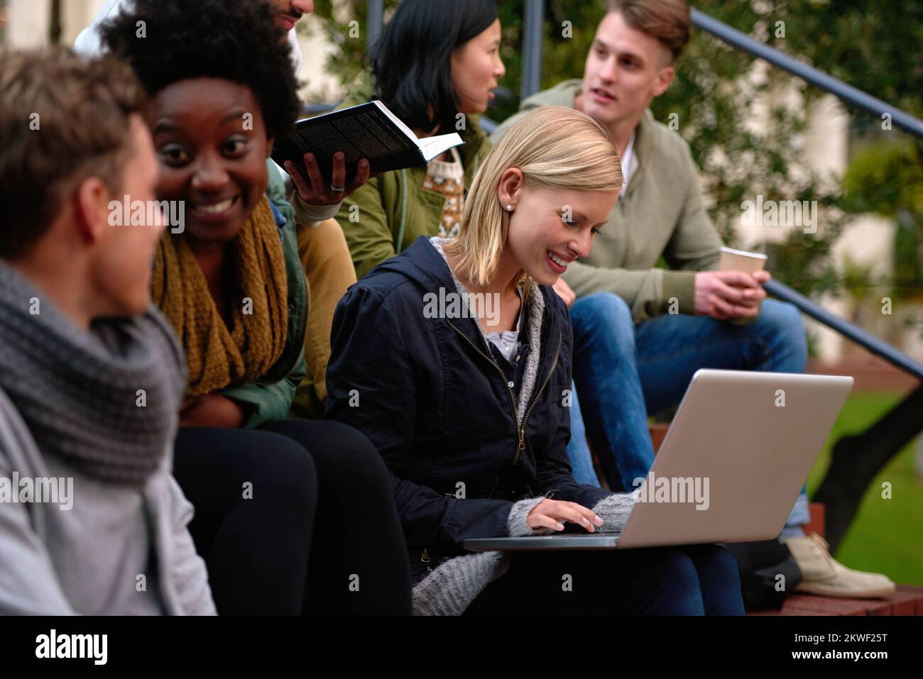 Working on her project. a group students looking at a laptop on campus ...