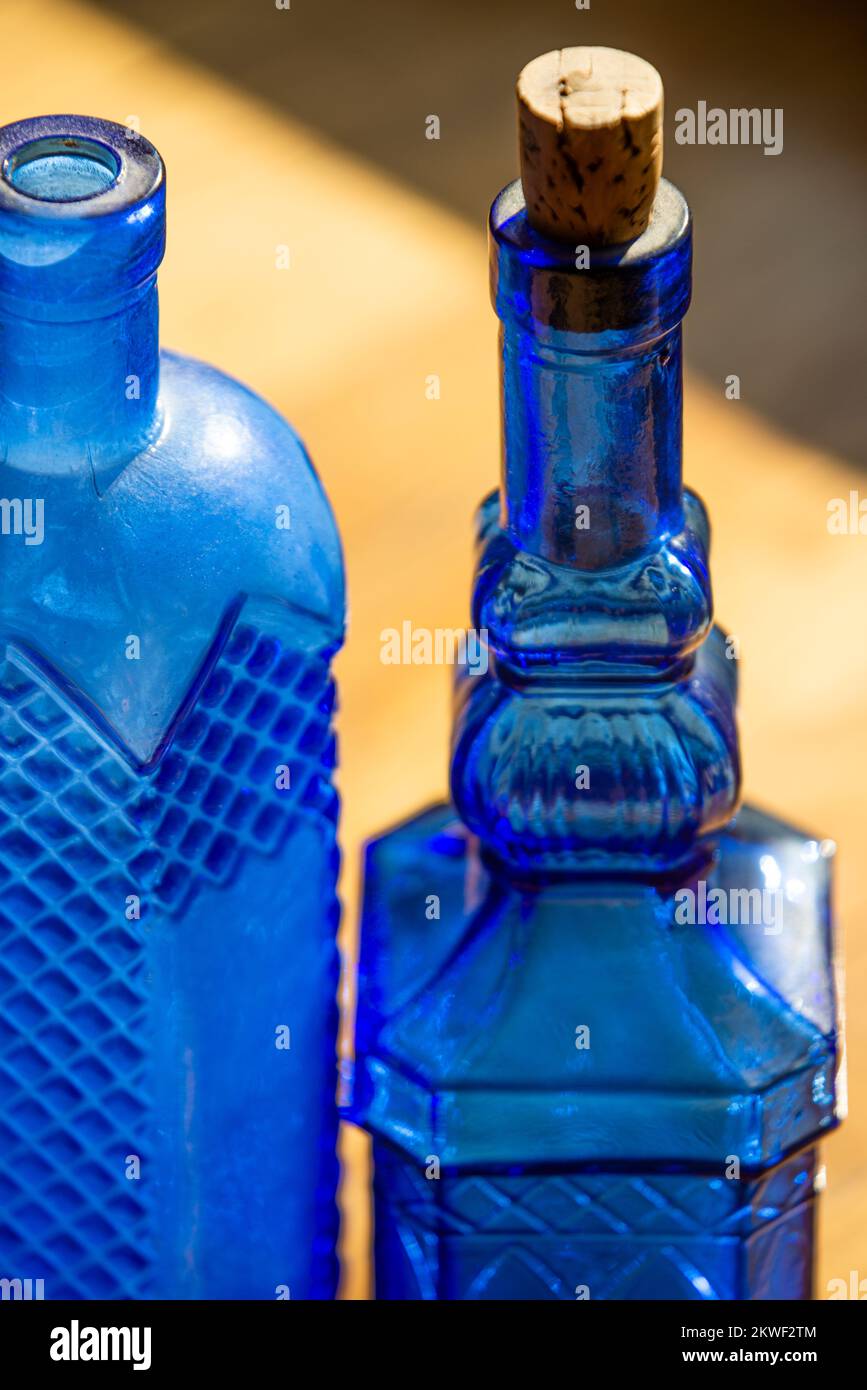 Vintage blue decorative glass bottles with a cork stopper in the light ...