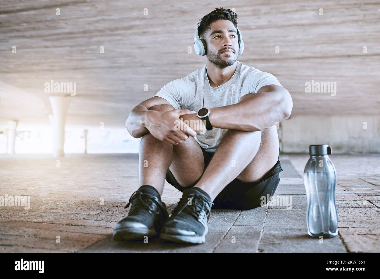 Athlete with headphones and water bottle on a relax break listening to ...
