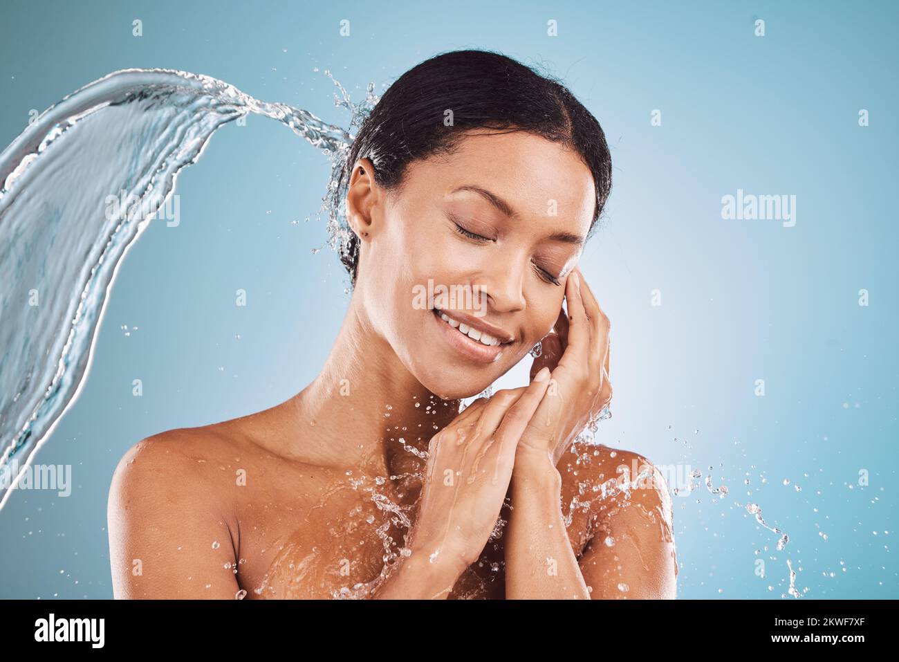 Beauty, water splash and skincare, black woman on blue background in ...