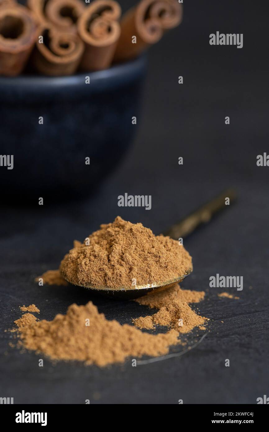 Natural Cinnamon sticks and cinnamon powder on dark concrete background ...