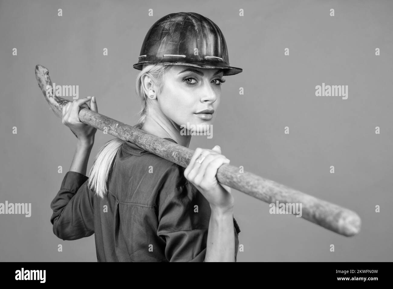 dig deeper. woman in boilersuit and helmet. female builder hold shovel ...