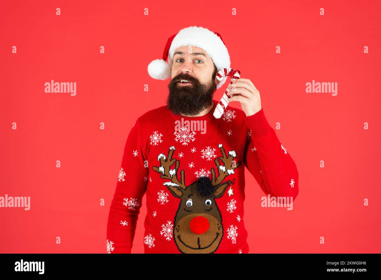 positive bearded guy in santa claus hat and sweater hold candy stick on ...