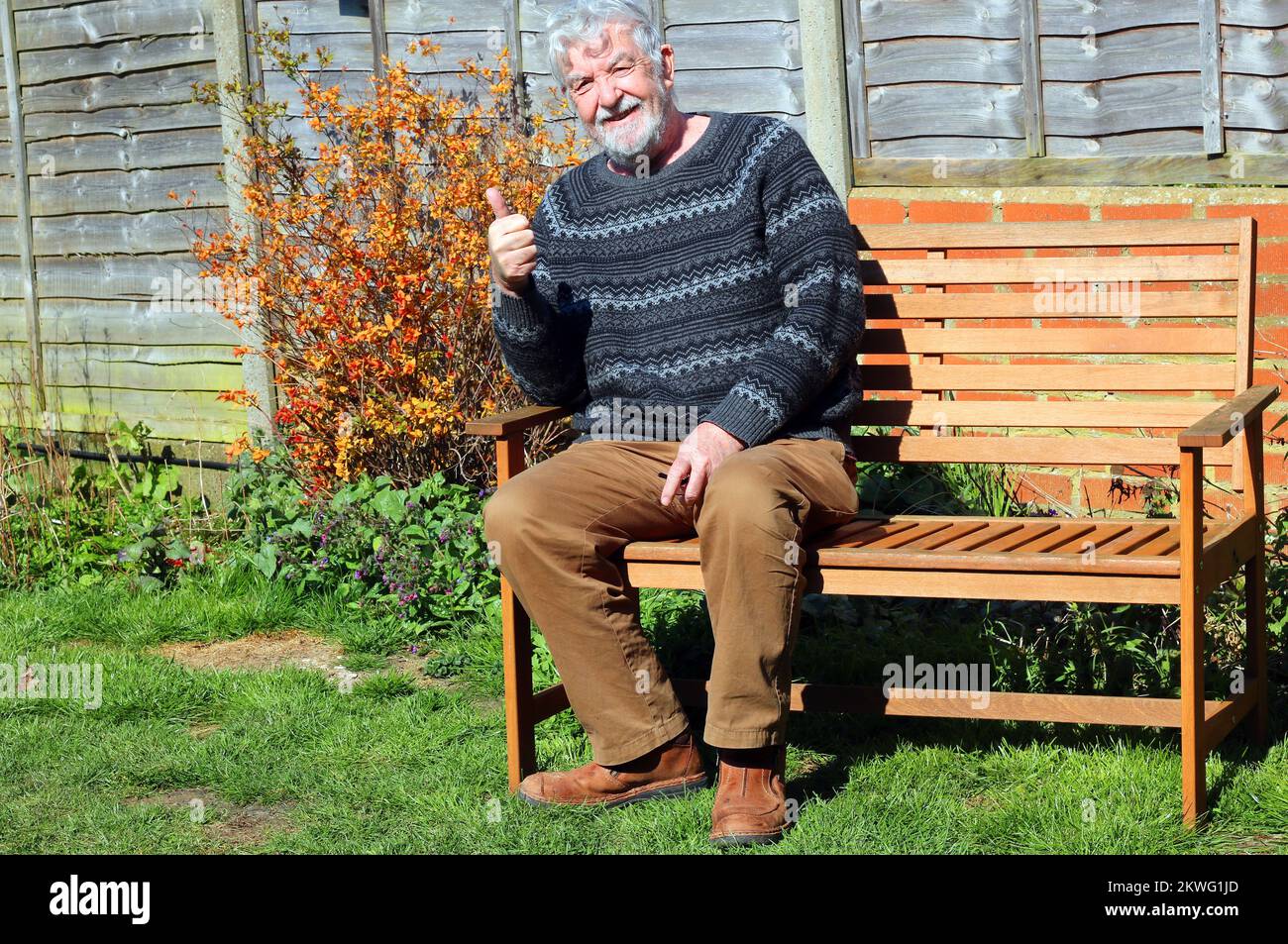 Elderly or senior man sitting on a bench and smiling, Making an ok sign ...