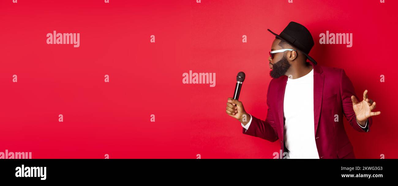 Passionate black male singer performing against red background, singing ...