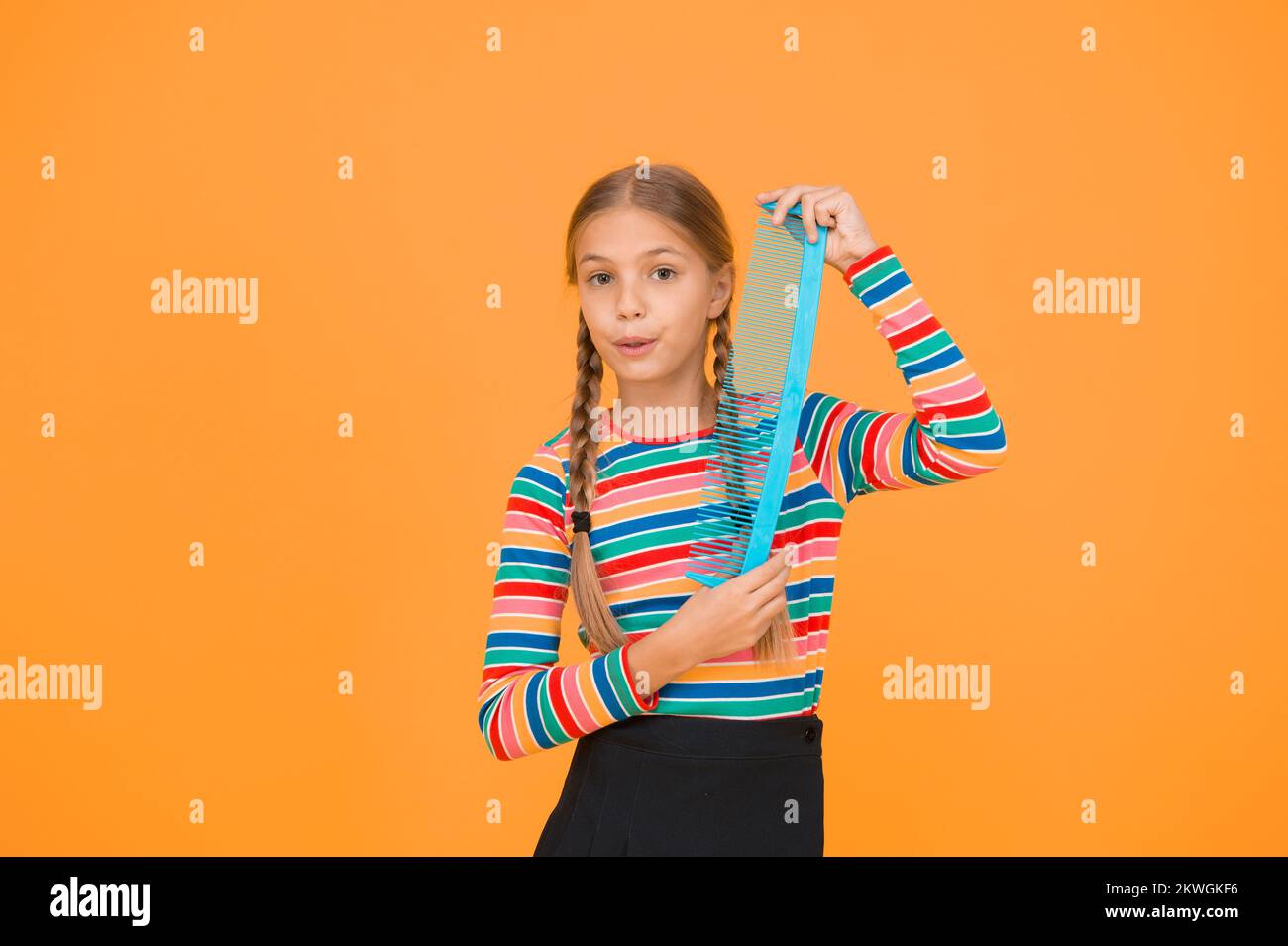 Shampoo hair first then comb. Small child hold comb yellow background ...