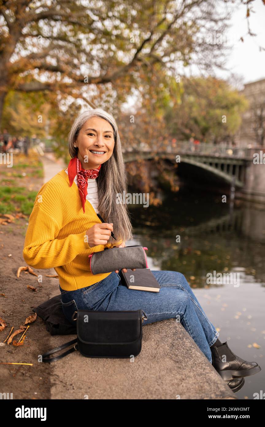 Woman sitting on the river bank and making notes Stock Photo - Alamy