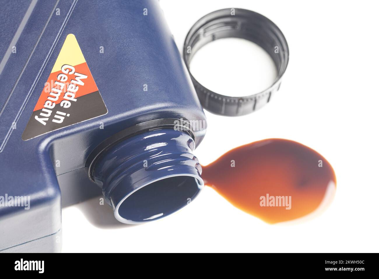open engine oil bottle with a puddle of engine oil isolated on white ...