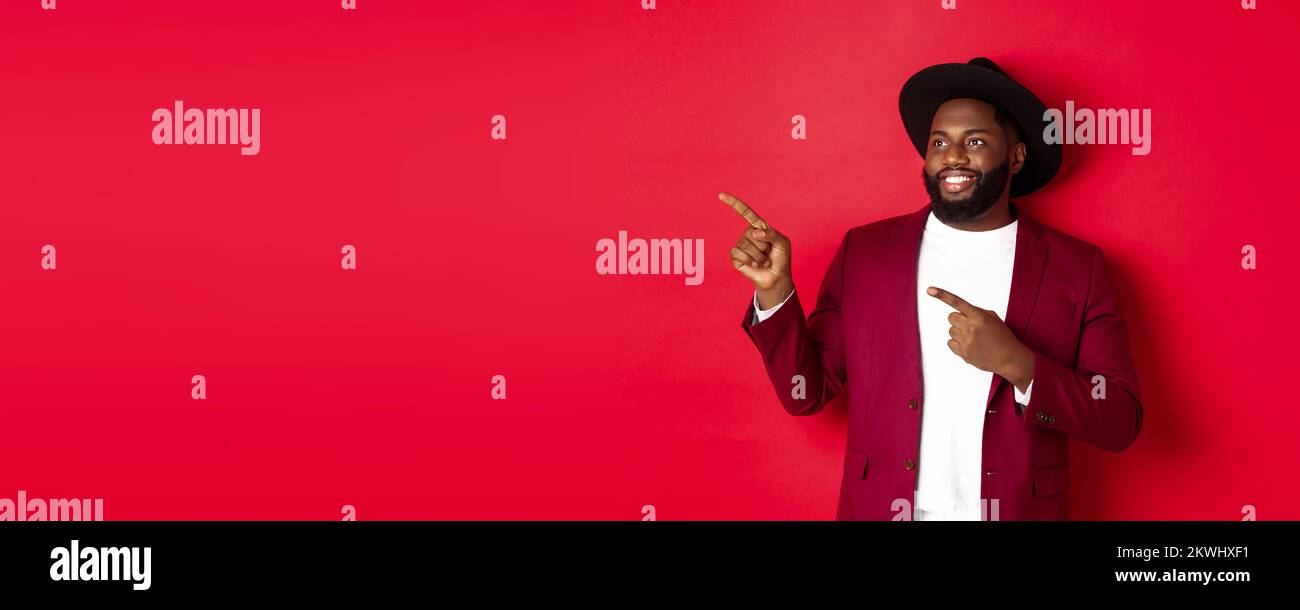 Winter holidays and shopping concept. Happy Black man pointing left and ...