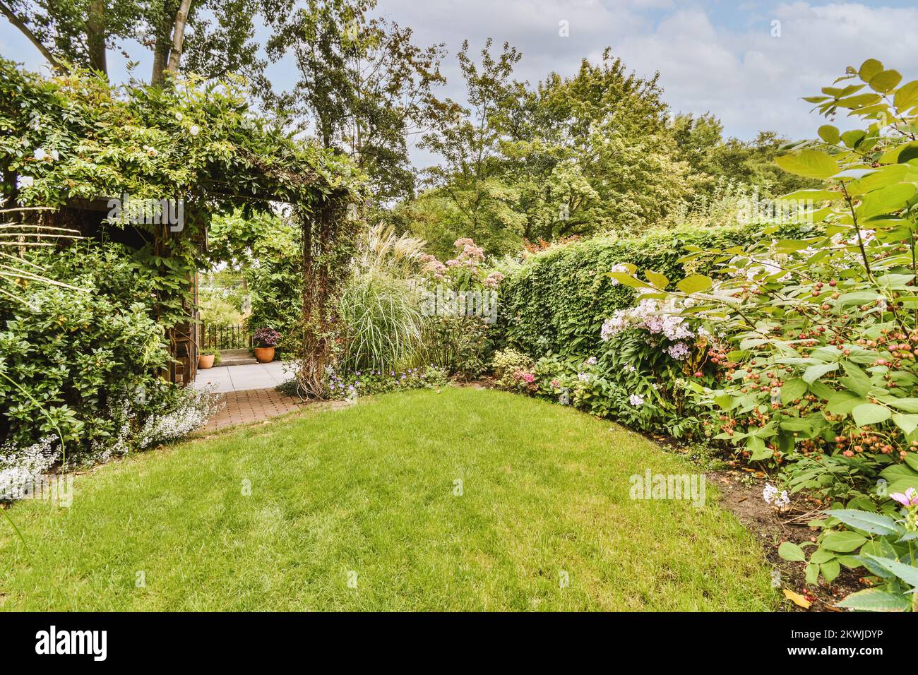 Neat paved patio with sitting area and small garden near wooden fence ...
