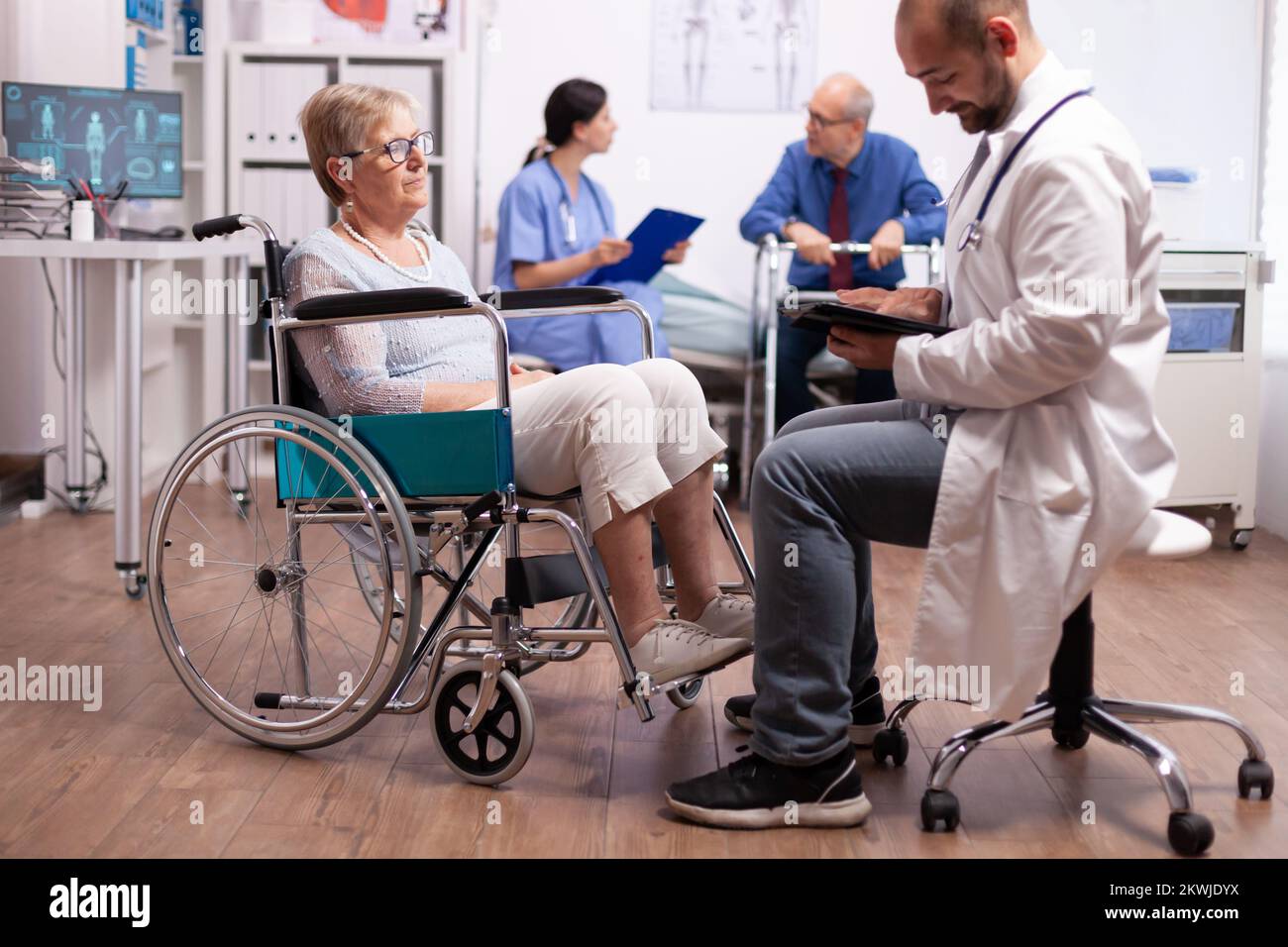 Medical physician discussing with handicapped senior woman sitting in ...
