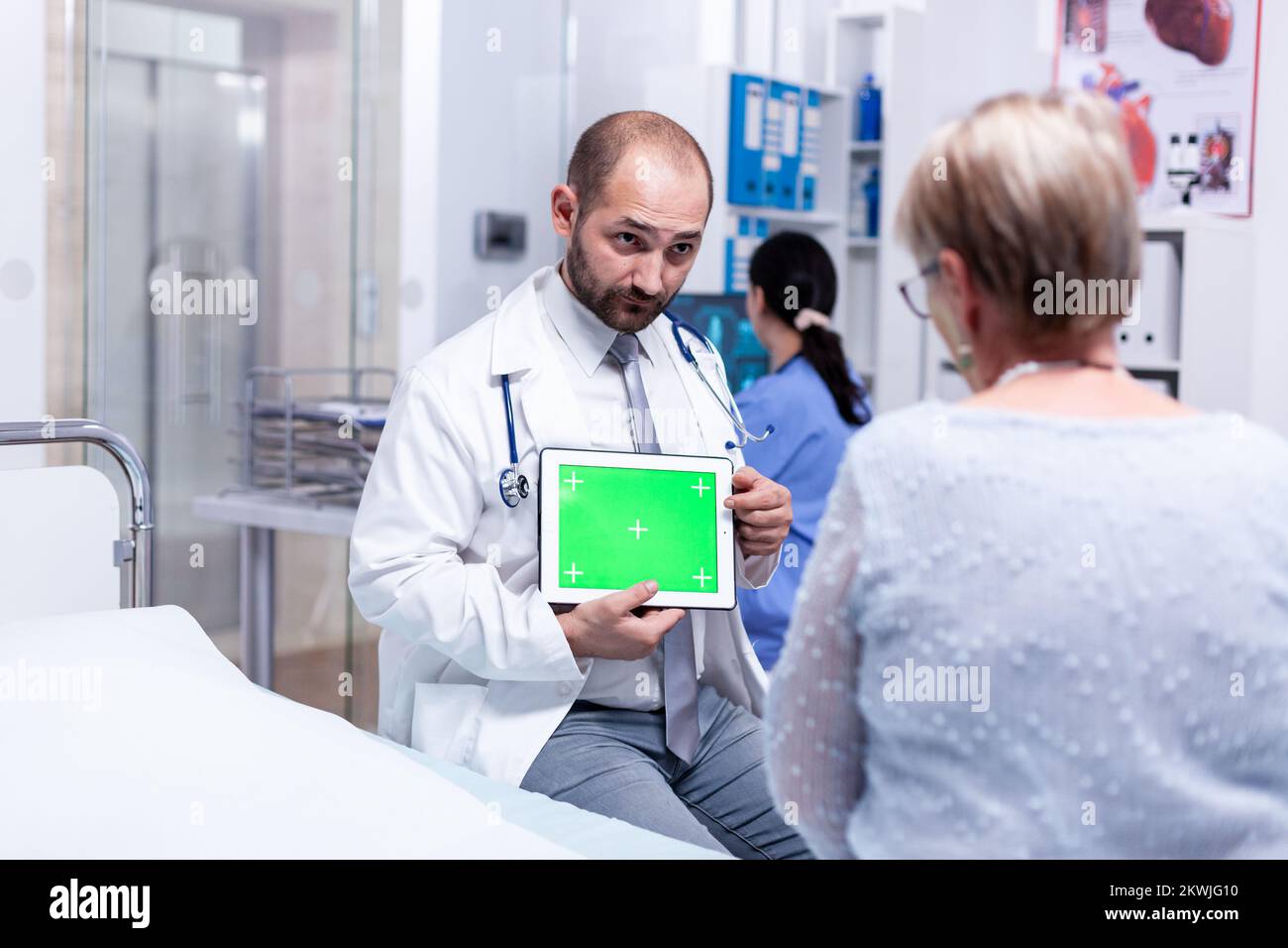 Doctor with green screen tablet in front of elderly patient explaining ...