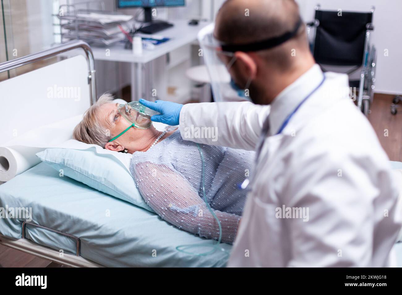 Doctor putting oxygen mask on senior woman laying in hospital during ...
