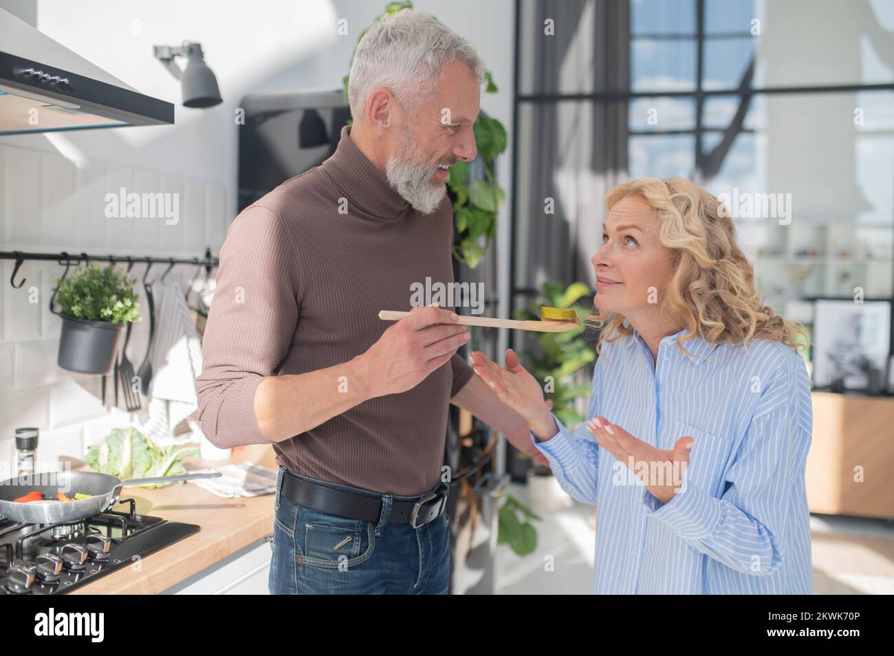 Man giving his wife some soup to try Stock Photo - Alamy
