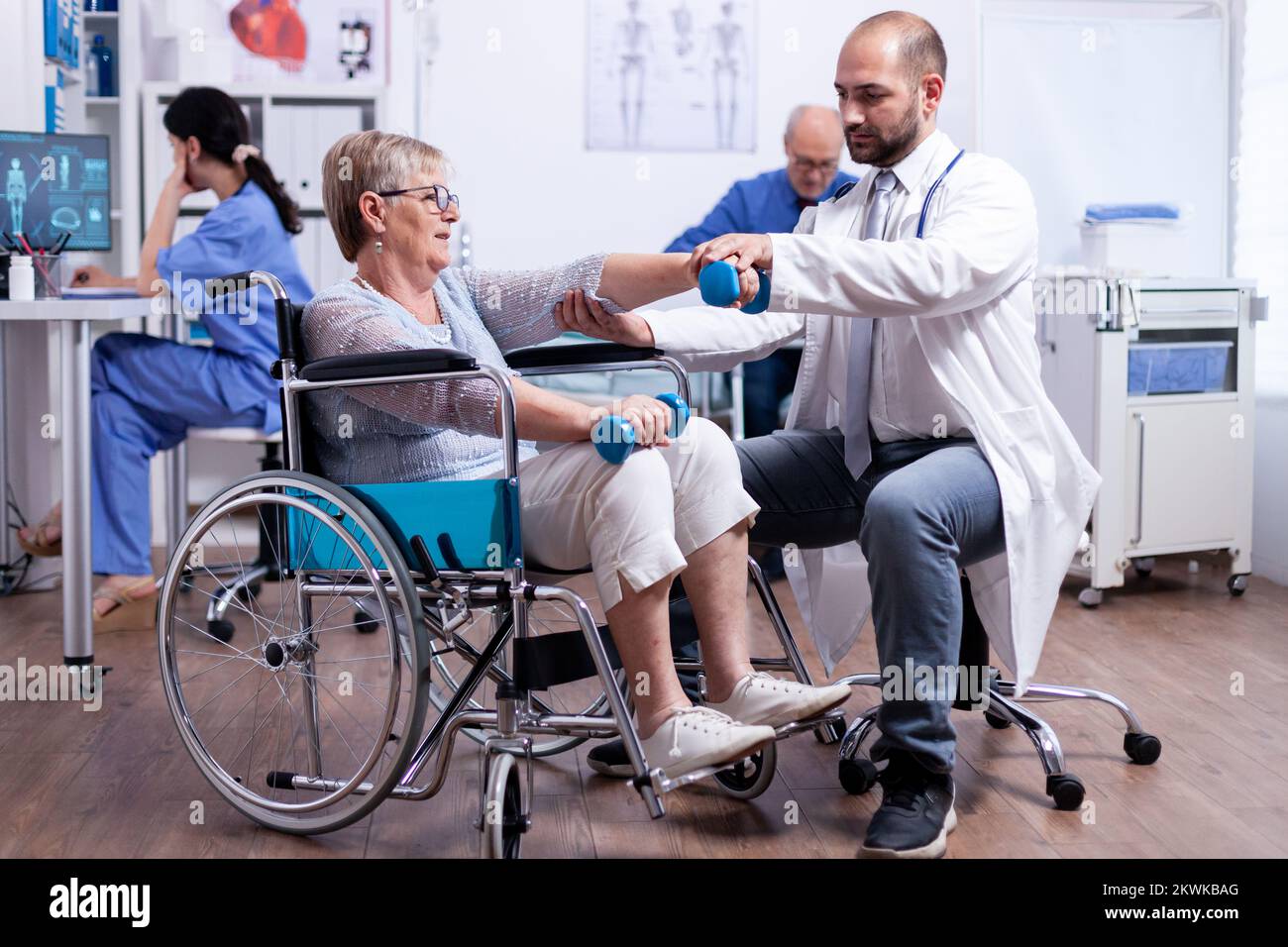Doctor helping old disabled woman in wheelchair to regain muscle ...