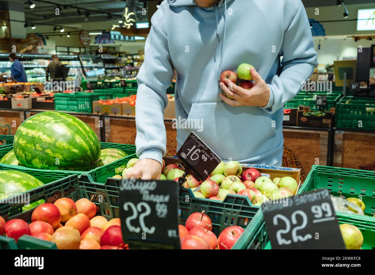 A man buys food, . A male customer chooses apples, taking products from ...
