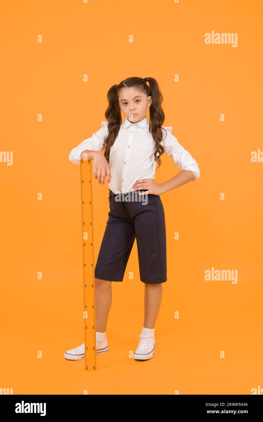 Where student comes first. Serious small student holding wooden ruler ...