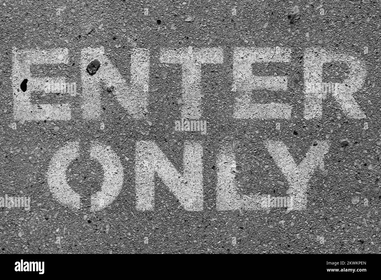 Enter only spray painted on the concrete sidewalkin a black and white ...