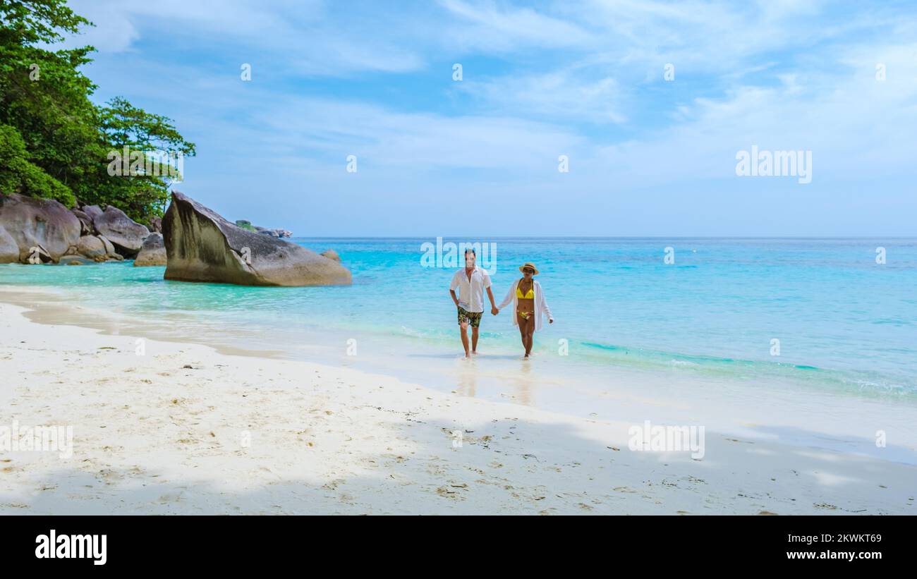 A couple of men and women on the tropical white beach with turqouse colored ocean of Similan ...