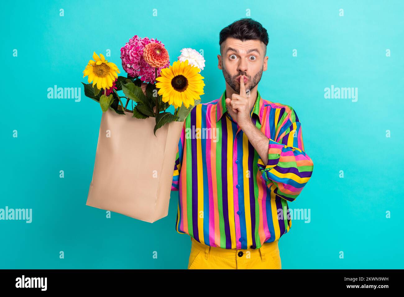 Photo of handsome guy hold flowers bag finger touch lips show do not ...