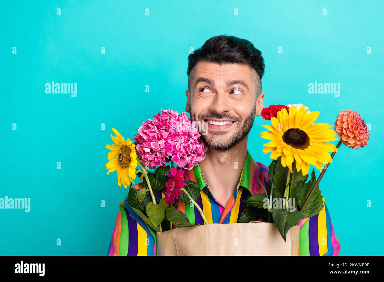Photo of minded man fresh flowers bags toothy smile look empty space ...