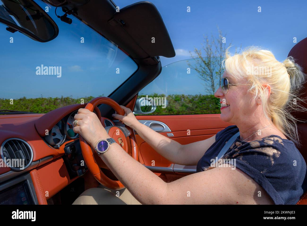 Blonde woman driving a Porsche sports car in the UK Stock Photo - Alamy