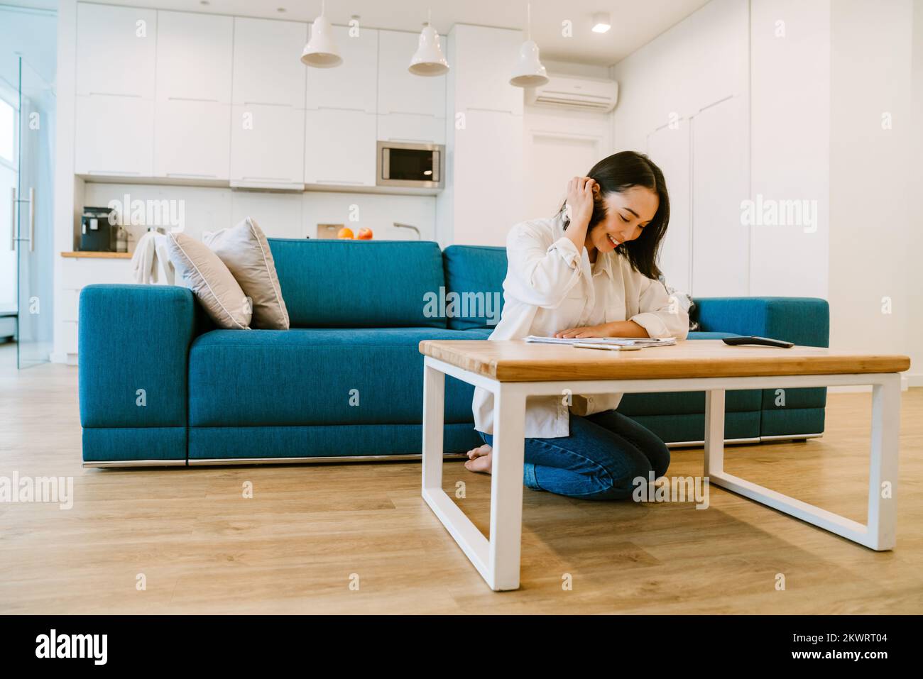 Young cute smiling asian woman adjusting hair and writing notes in cozy ...
